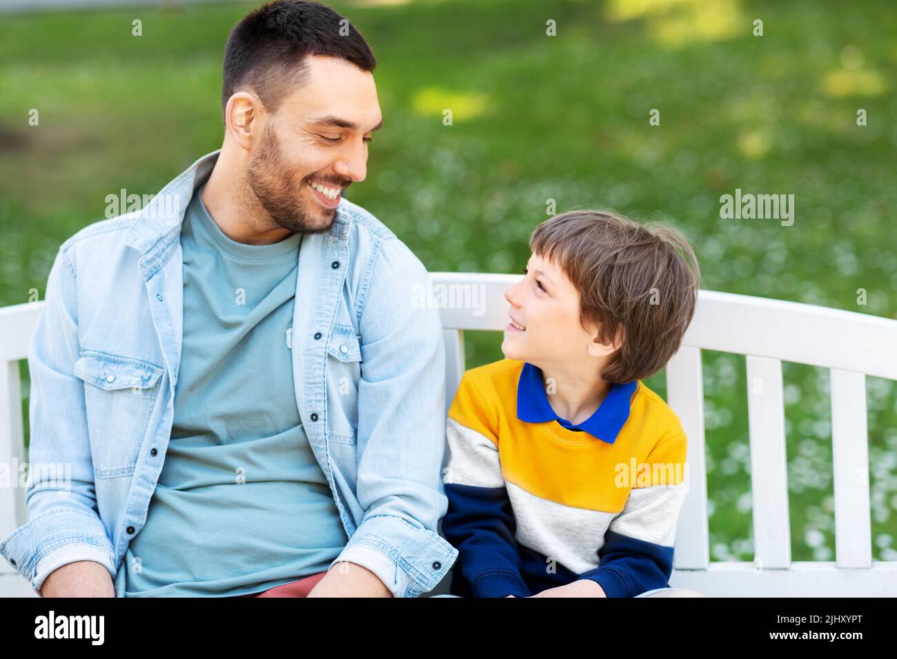 father with son sitting on park bench and talking Stock Photo - Alamy