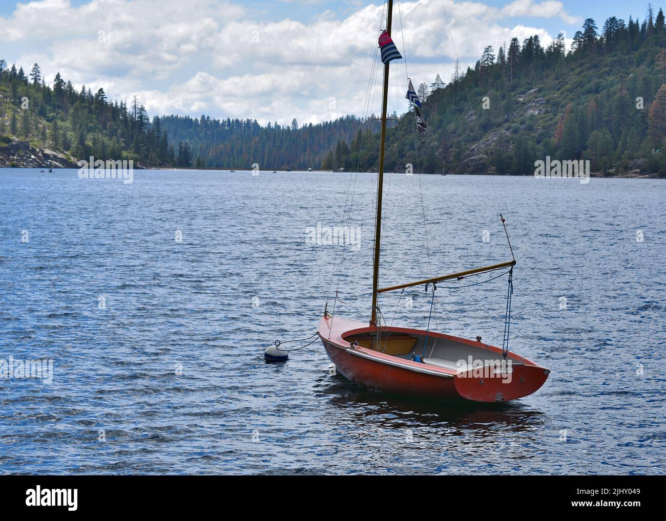 An old red boat in the middle of blue water and green cliffs in the ...