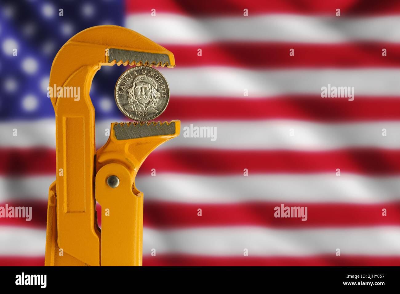 three peso coin held in an orange plumber wrench against the background ...