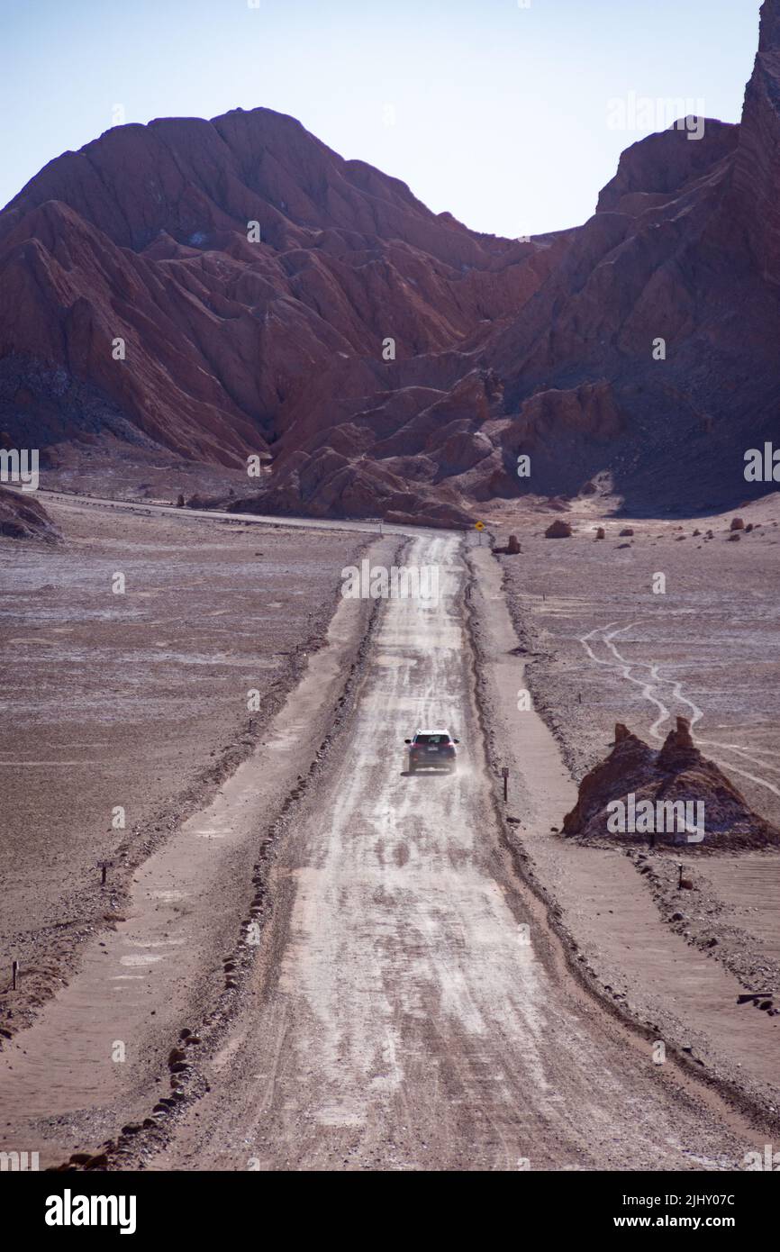 A vertical shot of a car on long road in the Atacama Desert under ...