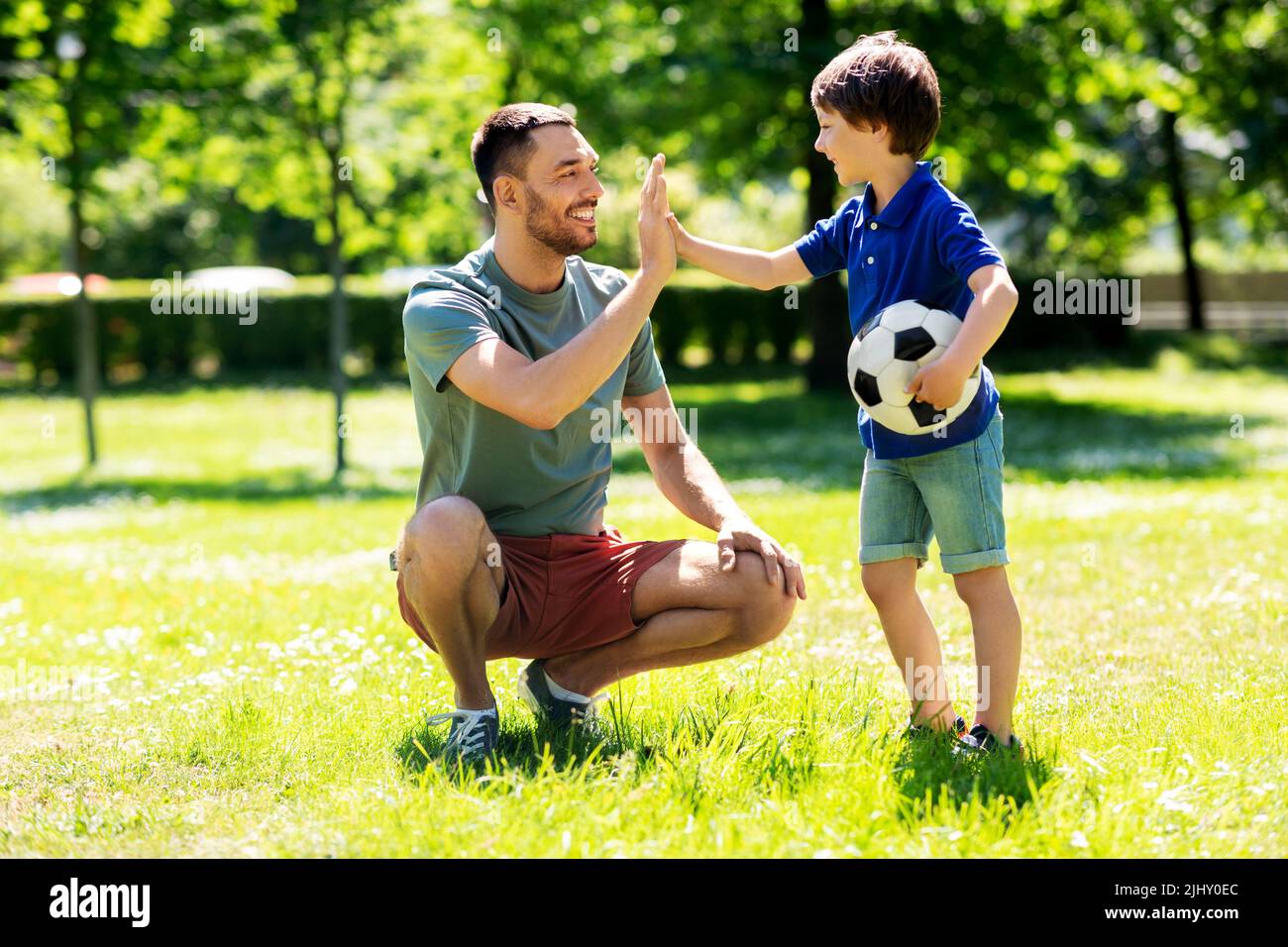 father giving five to son with soccer ball at park Stock Photo - Alamy