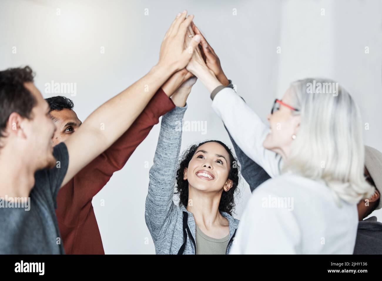 Diverse group of people standing together in circle and raising their ...