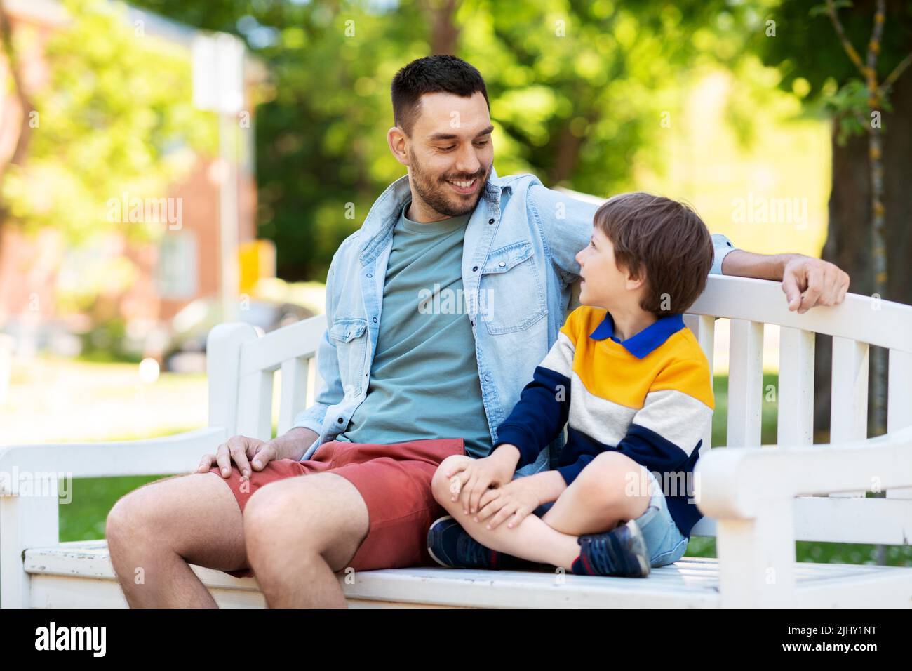 father with son sitting on park bench and talking Stock Photo - Alamy