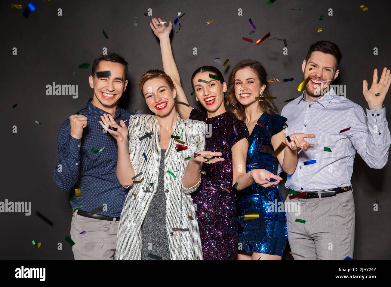 happy friends at party under confetti over black Stock Photo - Alamy