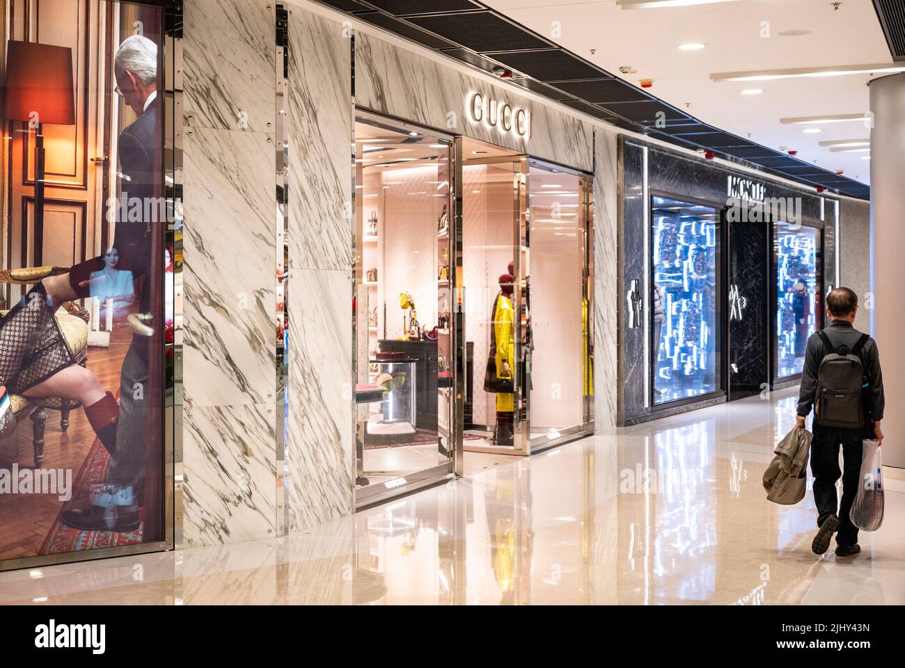 A shopper walks past the Italian luxury fashion brand Gucci logo and ...