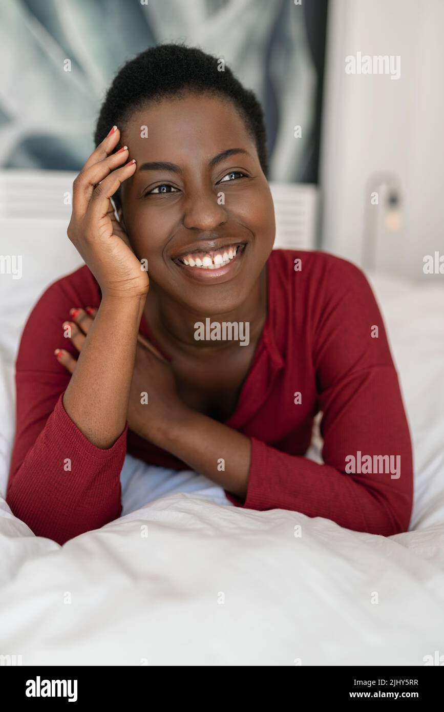 Close up portrait of beautiful Black African woman laying on bed with ...