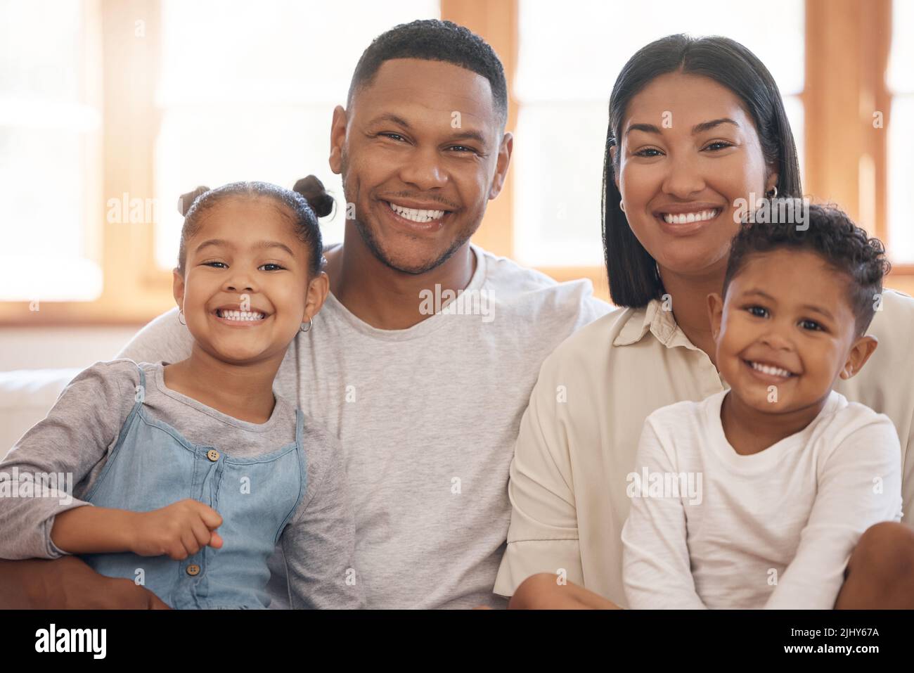 Portrait of a smiling young family of four at home. Mixed race mother ... Portrait of a smiling young family of four at home. Mixed race mother ...