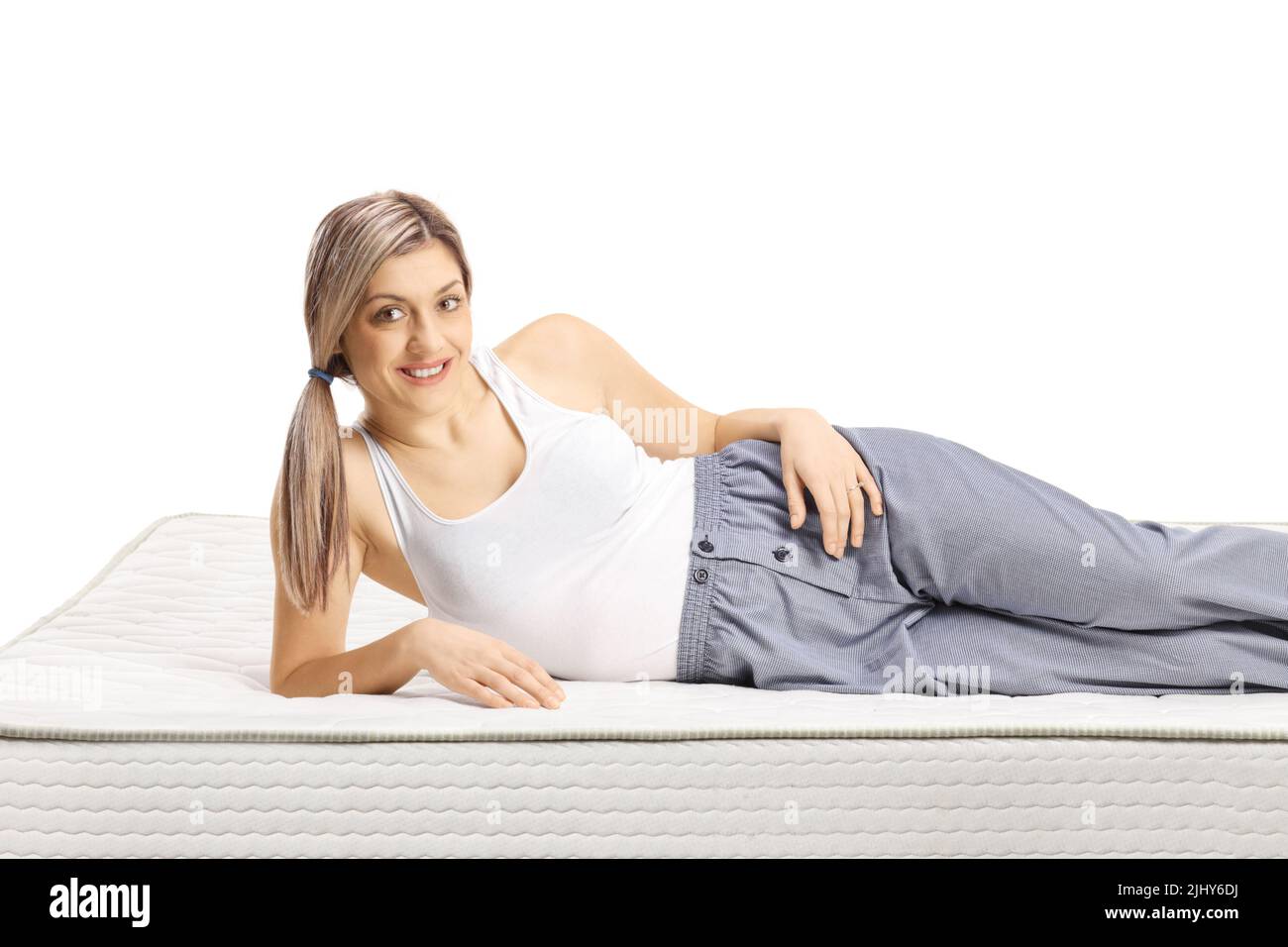 Woman lying on a bed mattress in pajamas and smiling at the camera ...