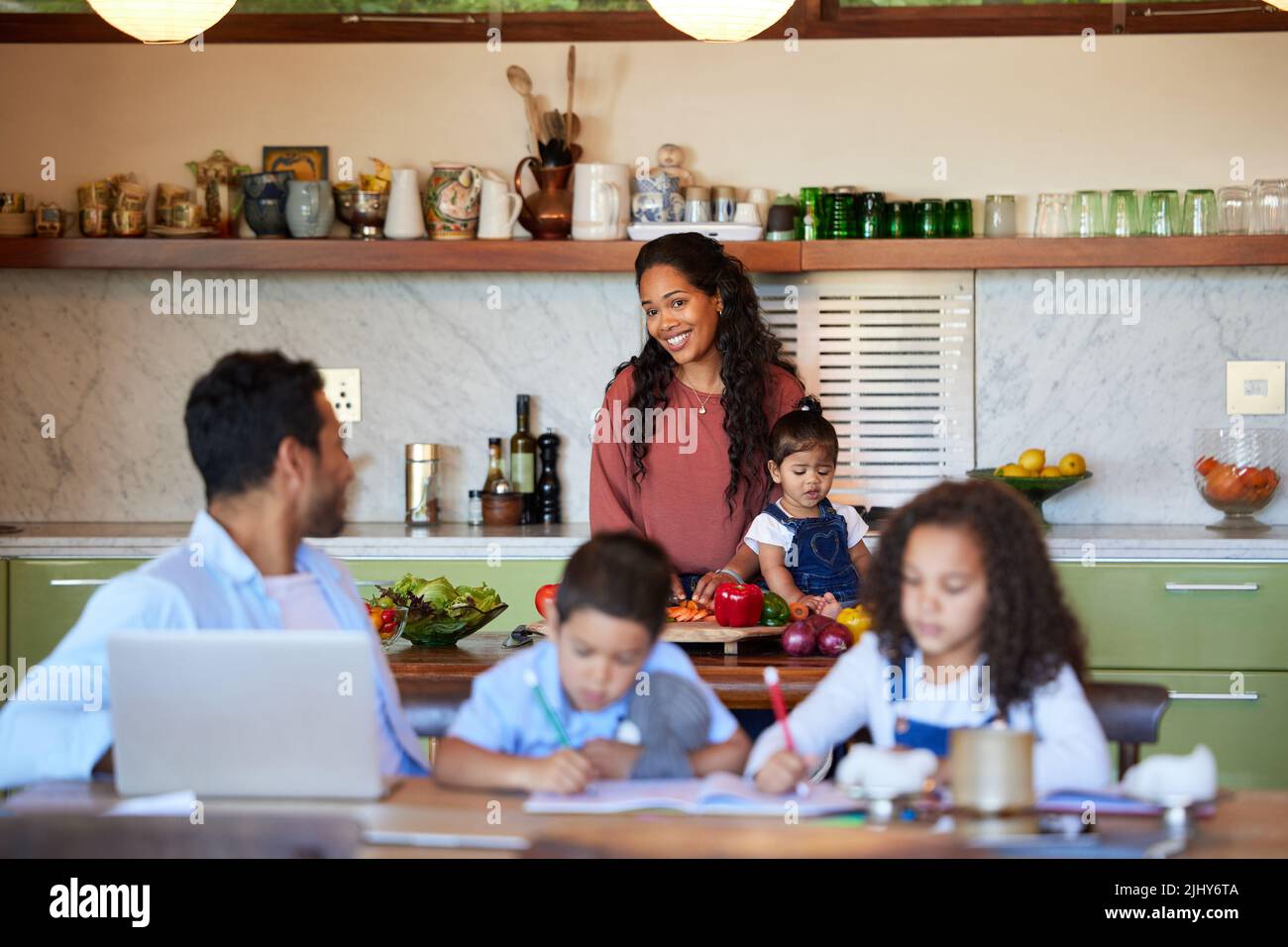 Happy mixed race mother cooking in the kitchen for her family. Dad ...
