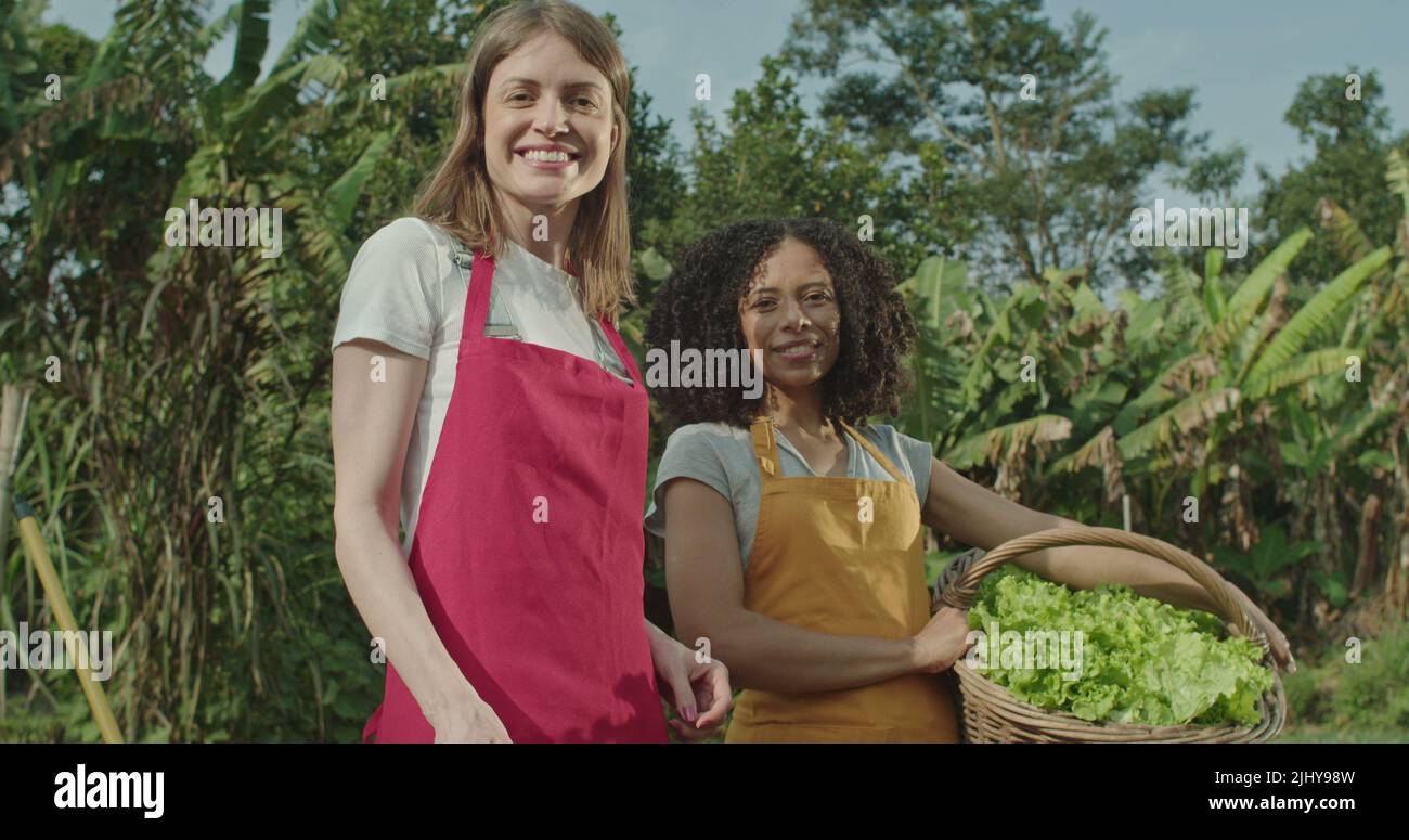 Portrait of two young diverse women farmers standing at organic ...