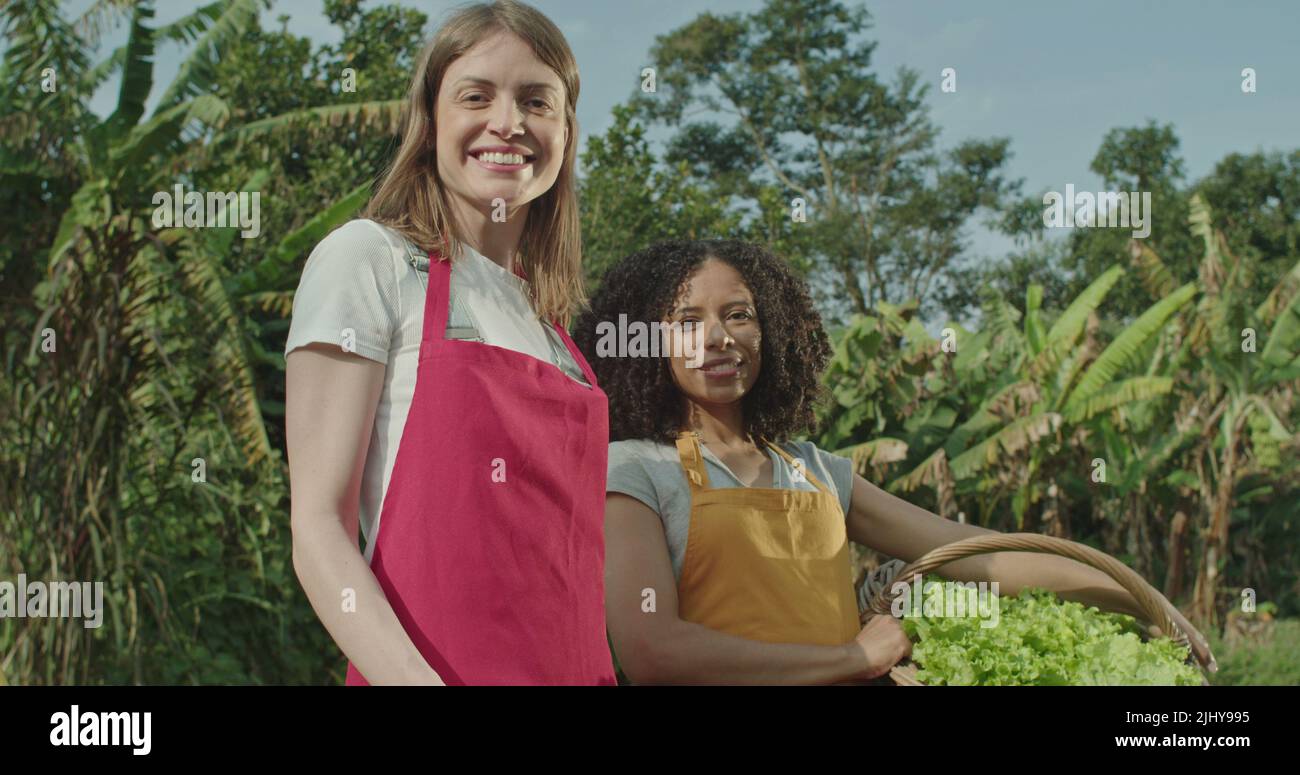 Portrait of two young diverse women farmers standing at organic ...