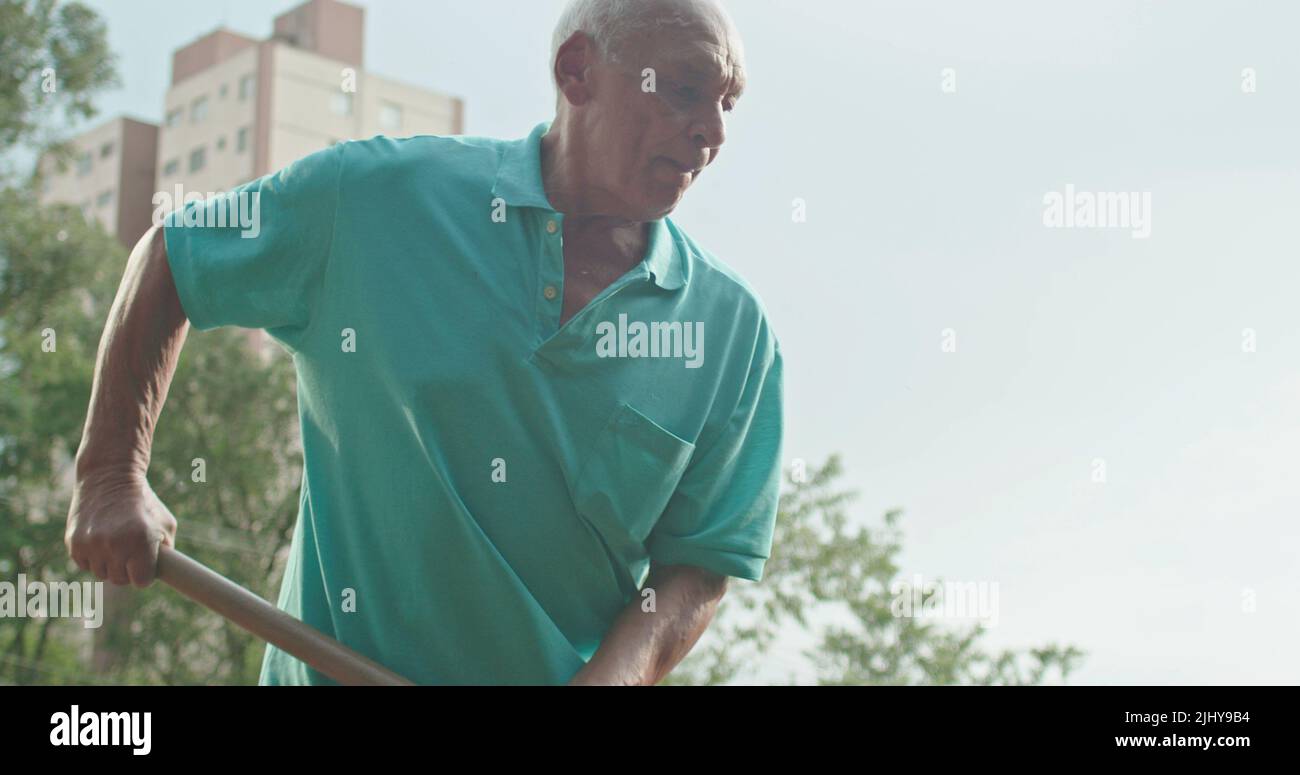 Person digging hole with farming equipment. A senior hispanic man digs ...