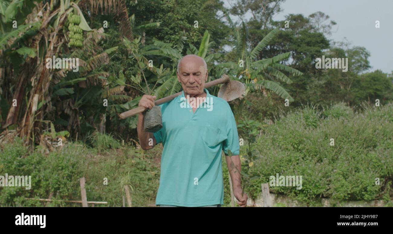A mature hispanic man carrying farming equipment and two potting ...