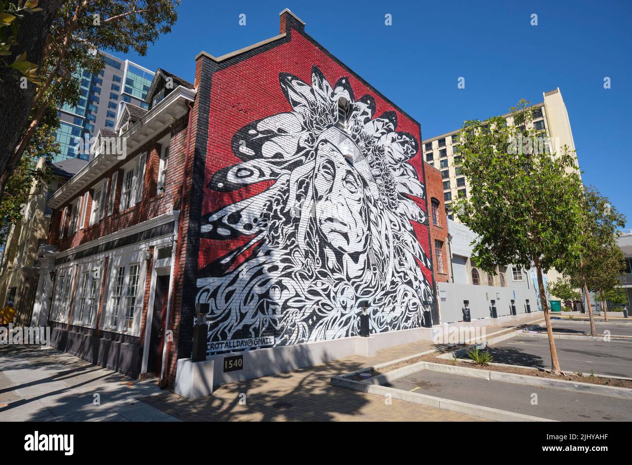 A huge mural on a red brick wall, featuring a portrait of a legendary ...