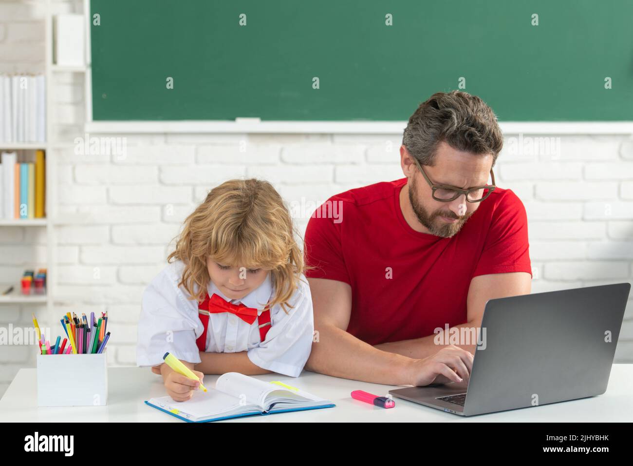 School pupil with teacher in classroom. Elementary school boy in ...