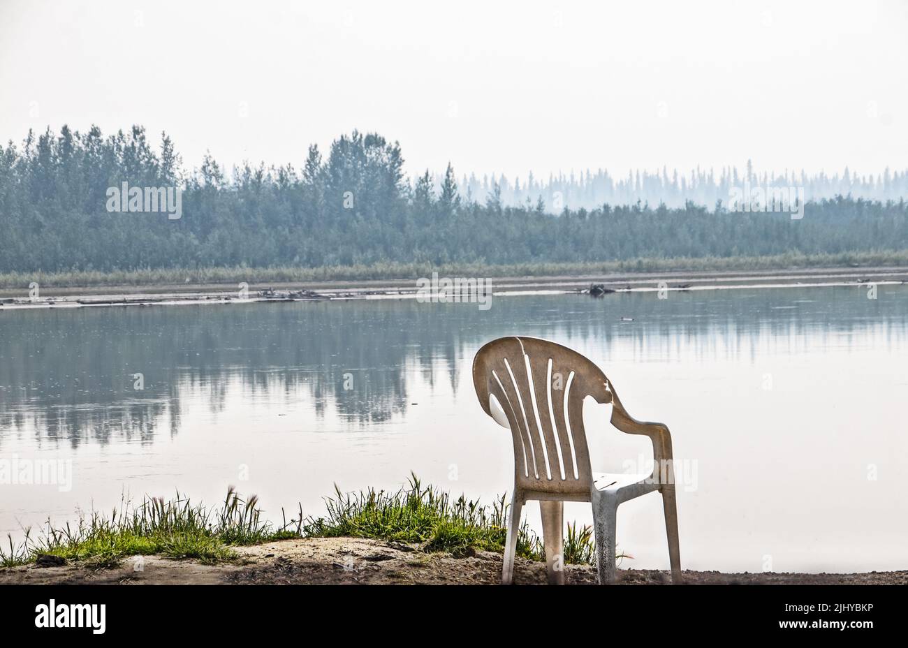 Alone - Old plastic chair beside pond on misty-smoky day in Fairbanks ...