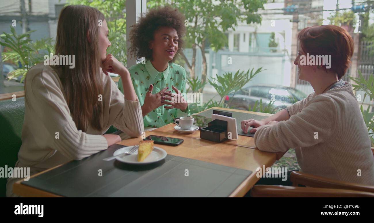Happy diverse female friends hanging out together at coffee shop. Three ...