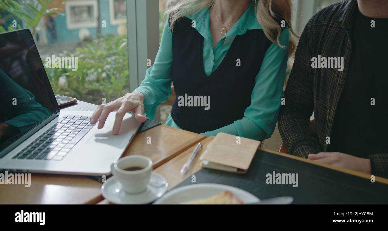 Senior executive female leader coaching younger employee in front of laptop. Closeup hand ...