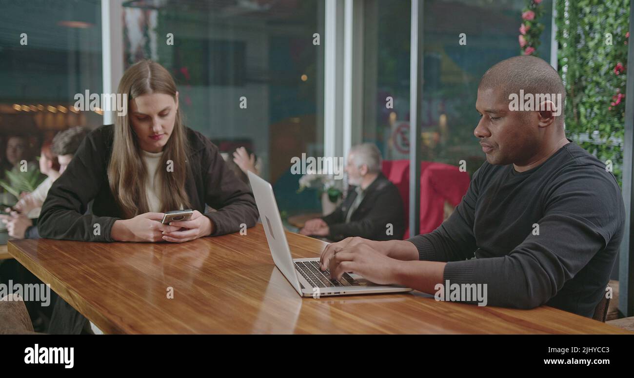 People sitting at coffee shop using modern technology devices. A black ...