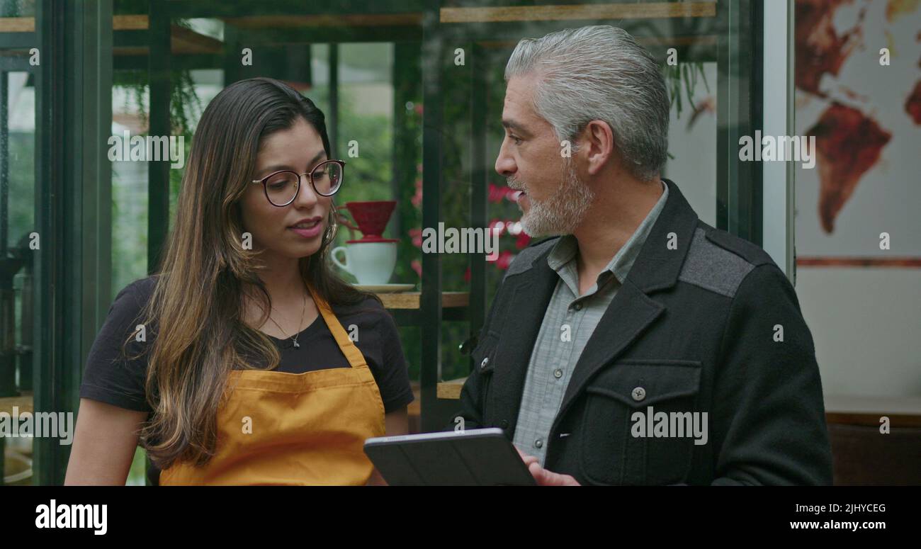 Small business owner speaking with female employee barista wearing ...