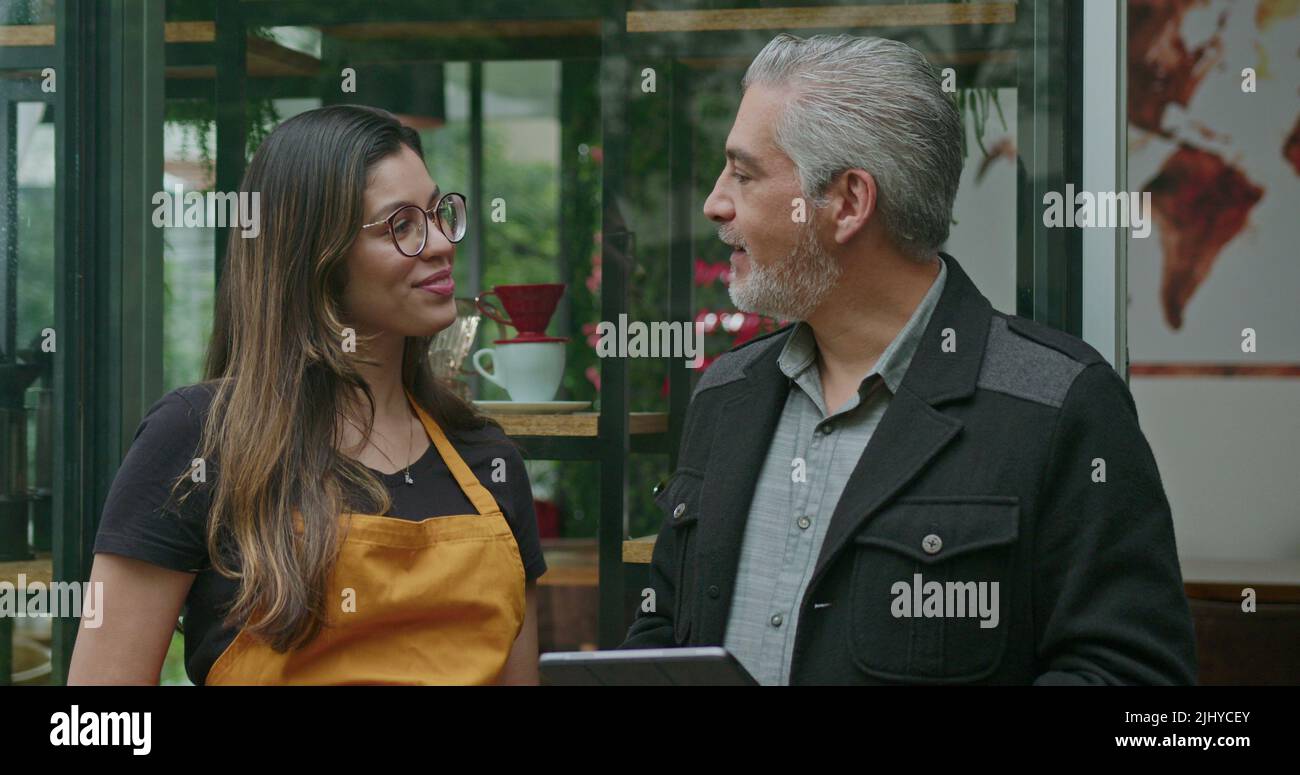 Small business owner speaking with female employee barista wearing ...