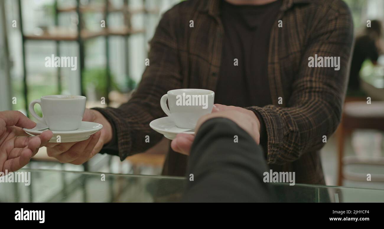Young man takes expressos at cafe counter. Client picking up coffee at ...