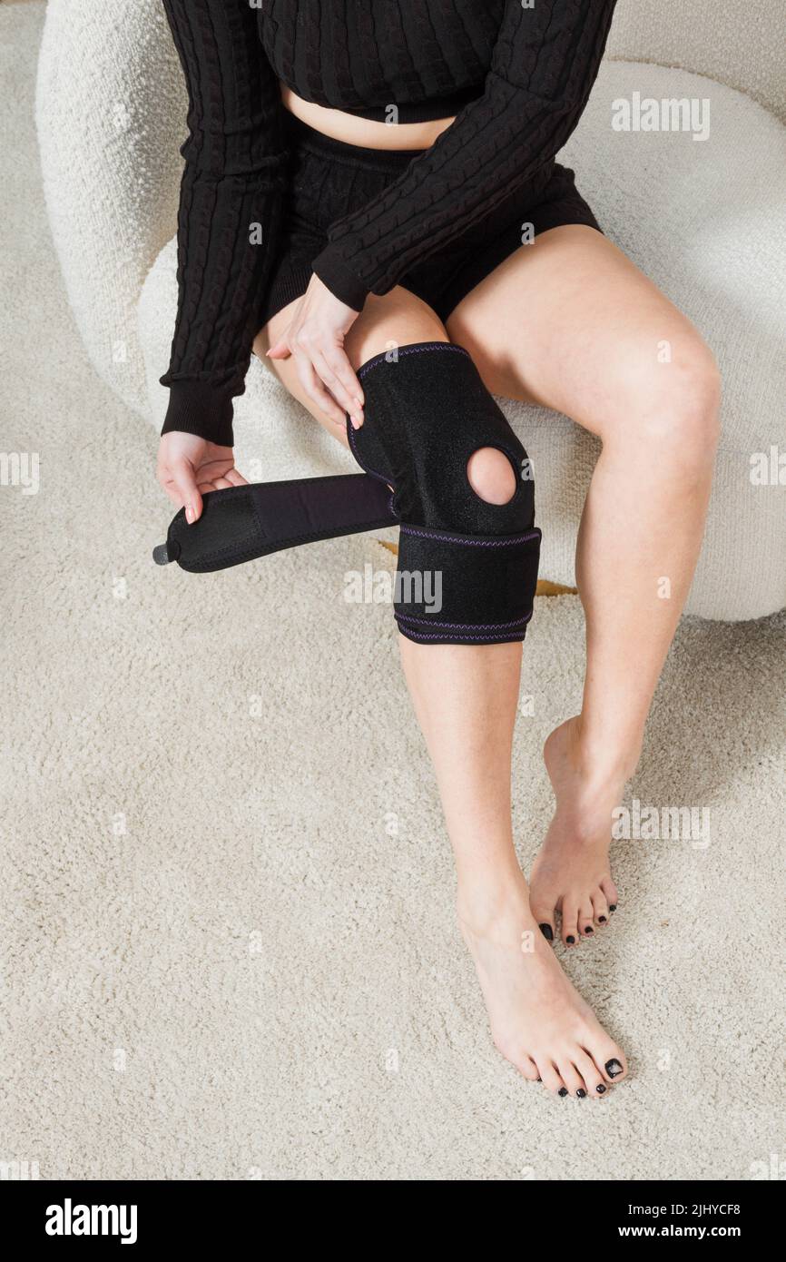 Black knee support brace on a woman leg. girl in an orthosis in the ...