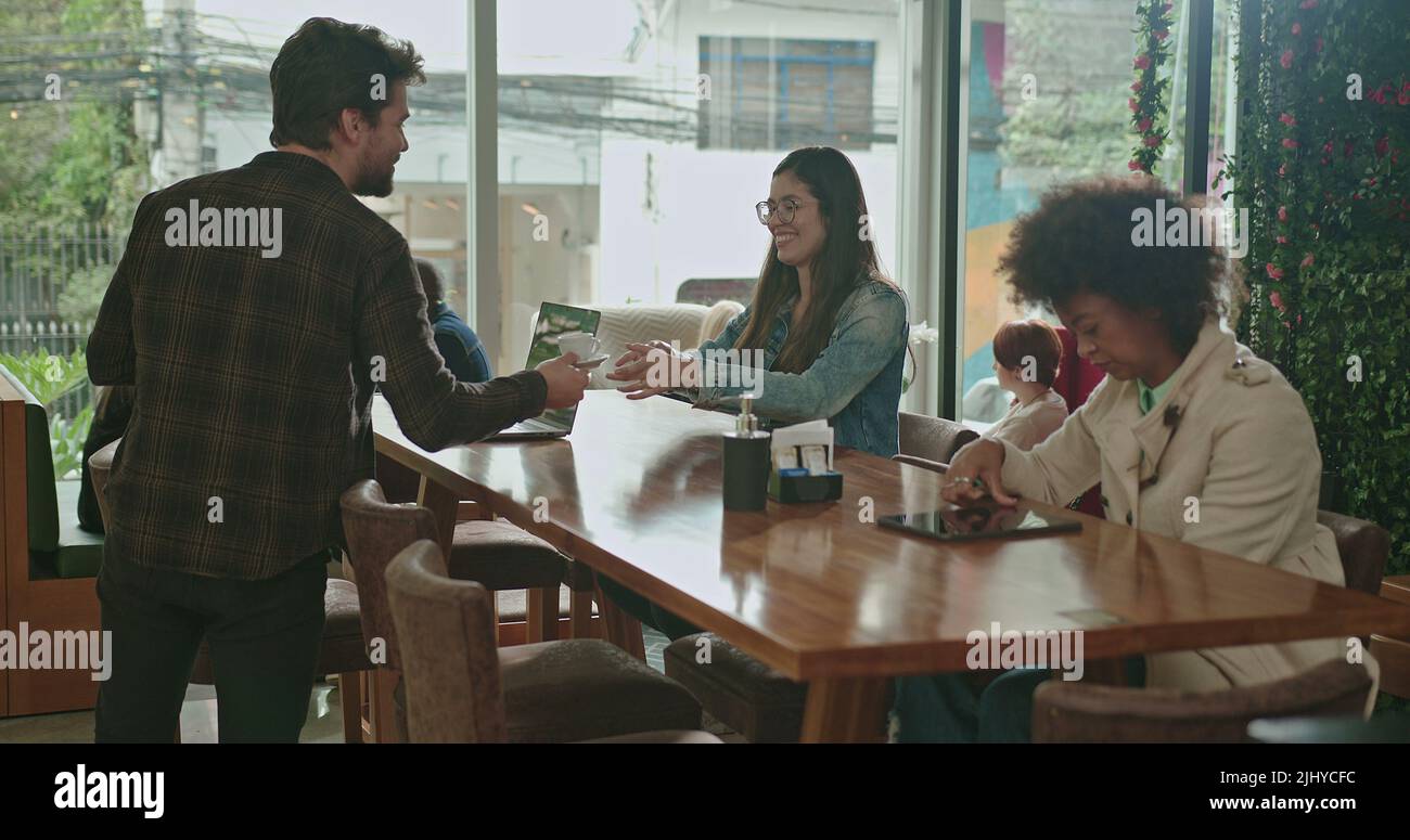 People sitting inside coffee shop drinking cafe. Local business ...