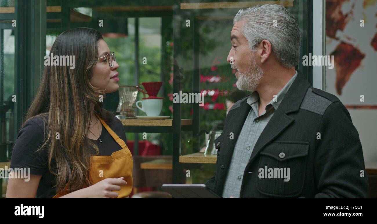 Small business owner speaking with female employee barista wearing ...