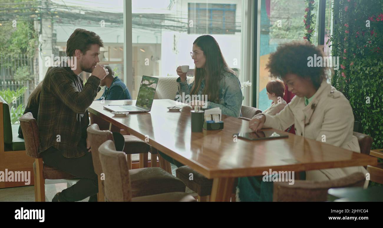 People sitting inside coffee shop drinking cafe. Local business ...