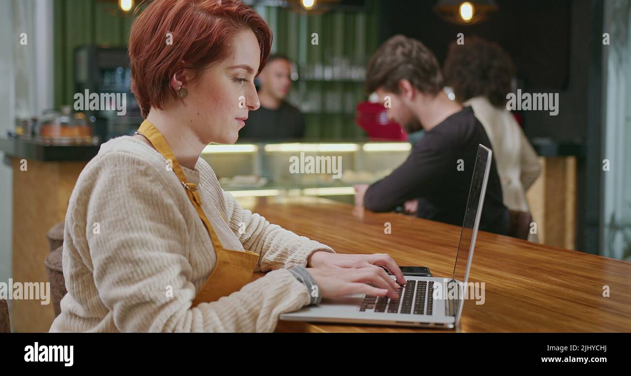 Young female employee opening laptop computer sitting inside coffee ...