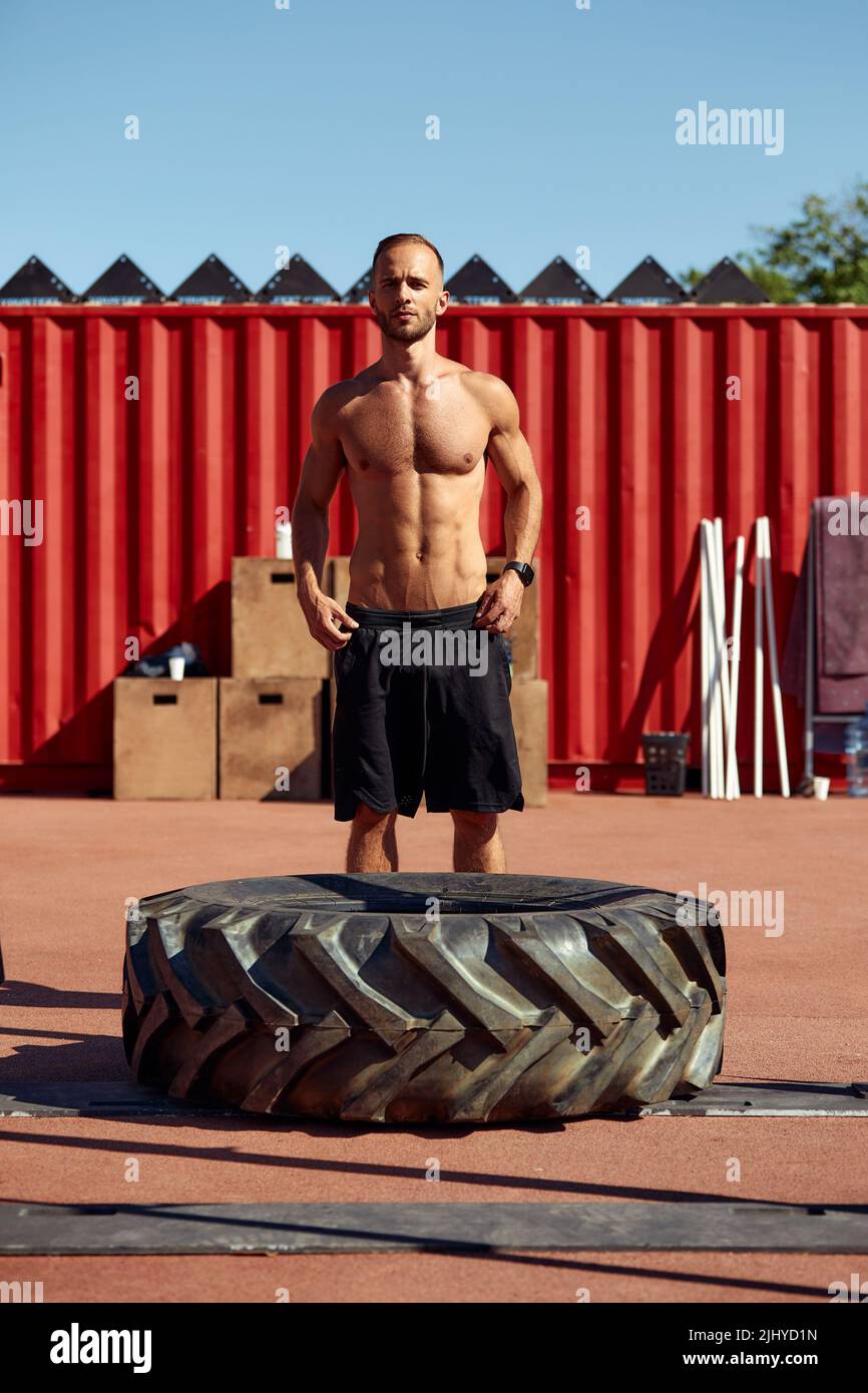 Strong man training workout lifting large tire outdoor gym. Sportive ...