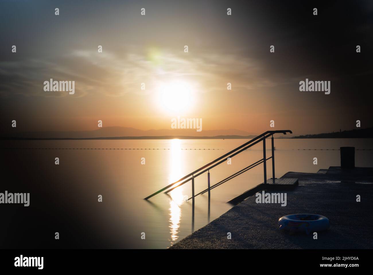Railing of a bathing ladder against the light of the setting sun Stock ...