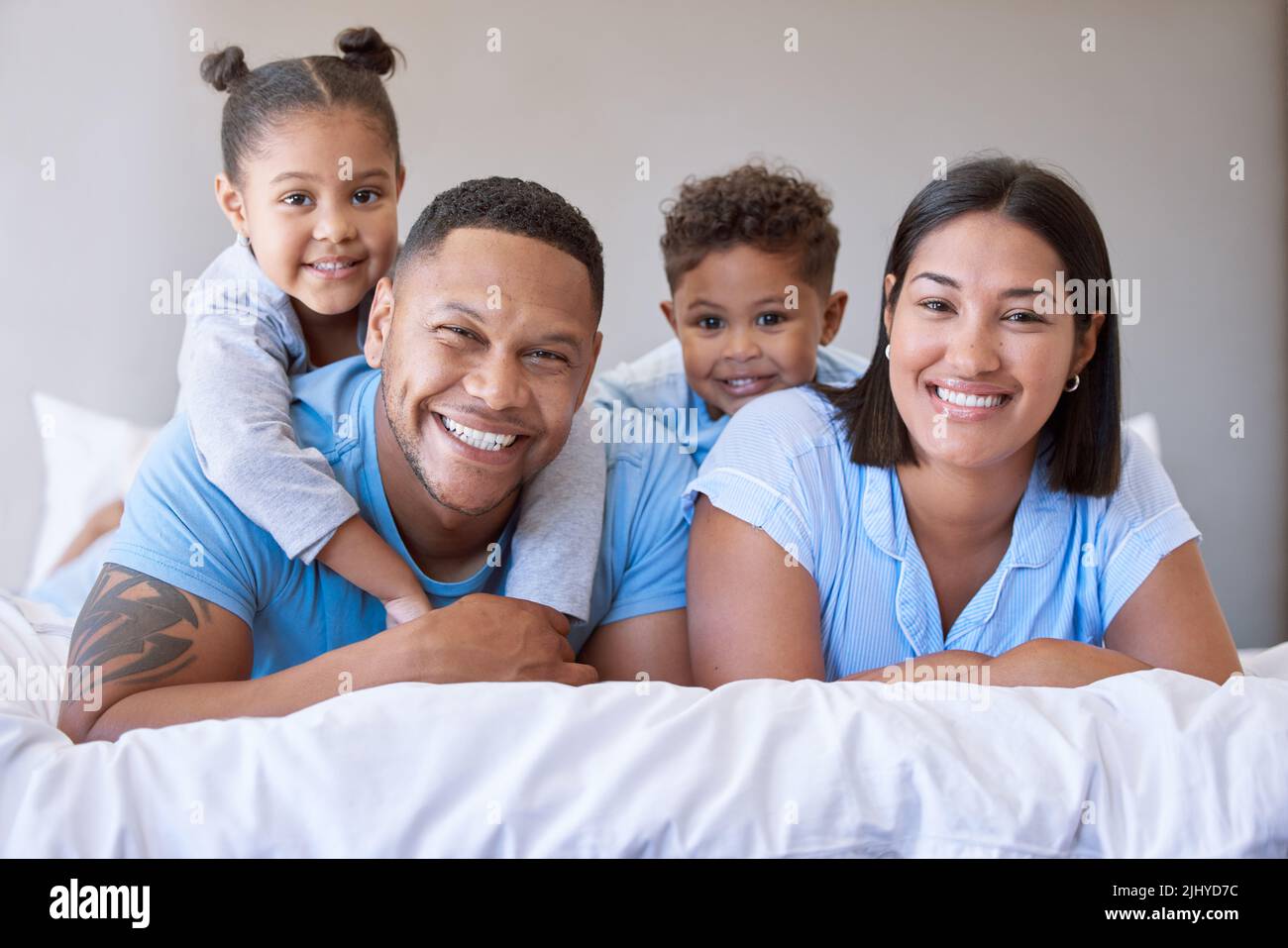 Portrait of a smiling boy and girl lying on their parents in a bed at ...