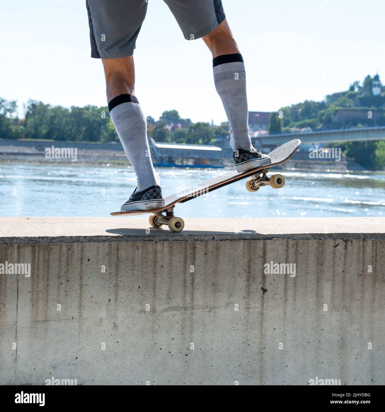 A selective of male hands on a skateboard on a stone wall facing the ...