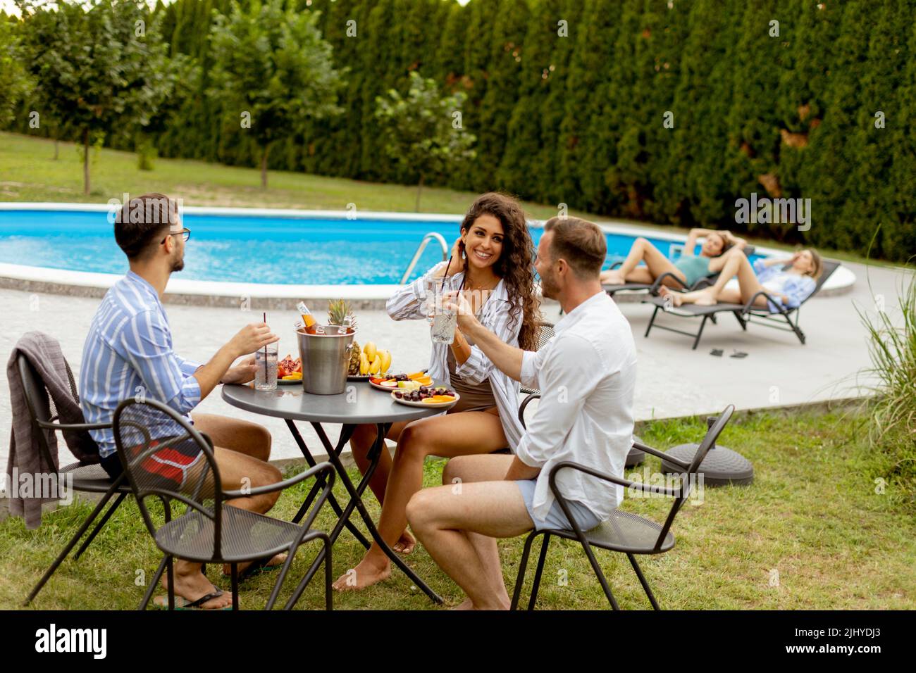 Group of happy young people cheering with drinks and eating fruits by ...