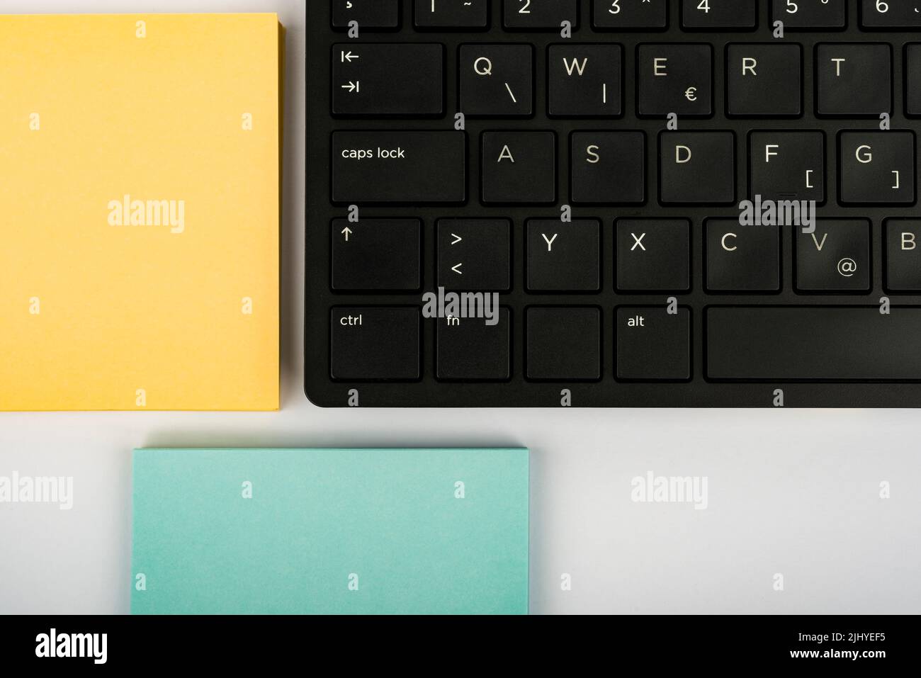 A part of a black computer keyboard, and two sets of sticky papers ...