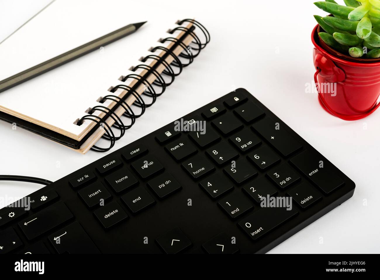 A part of a black computer keyboard, a notepad and other office ...