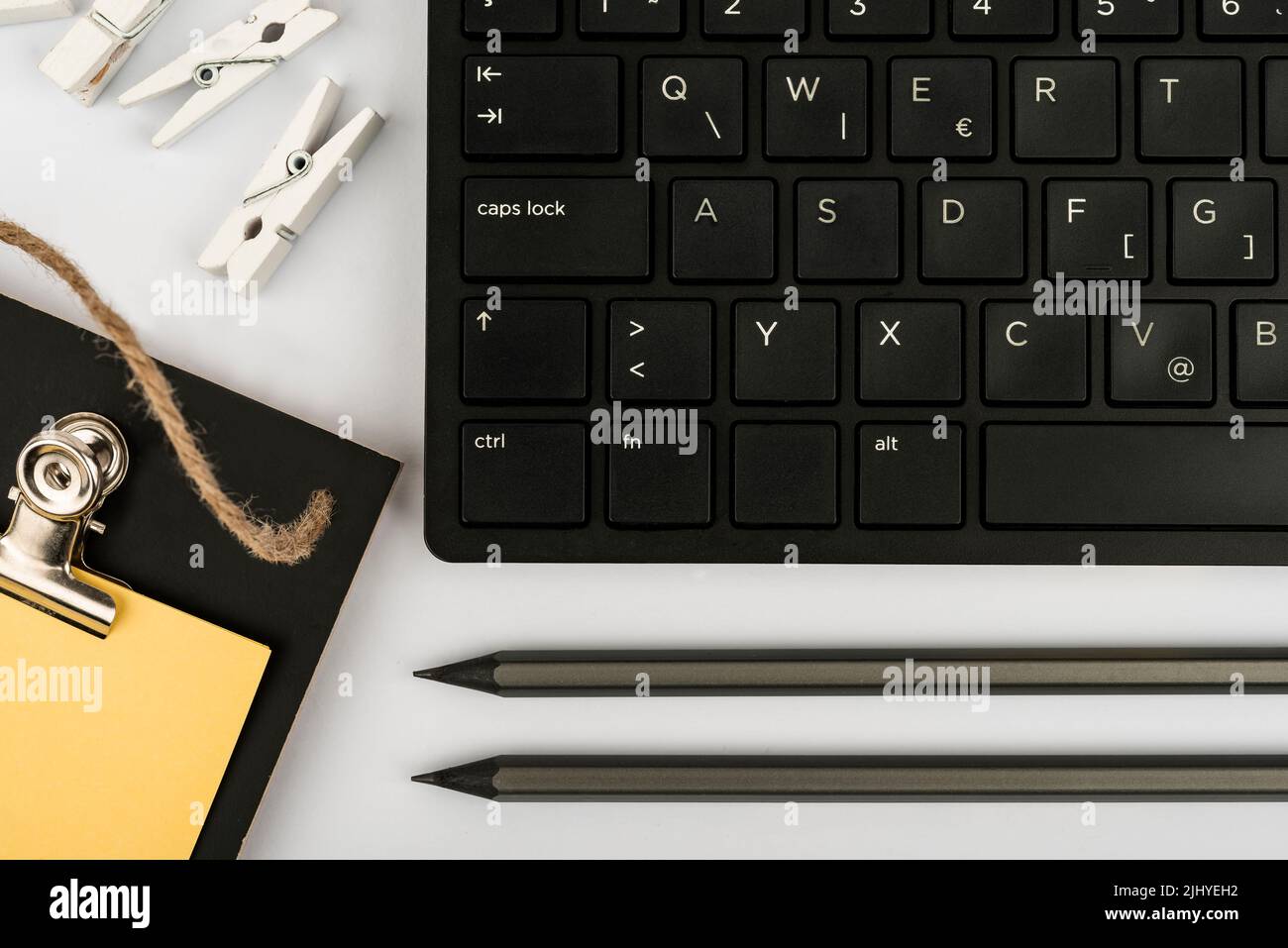 A part of a black computer keyboard, small paper pins and pencils ...