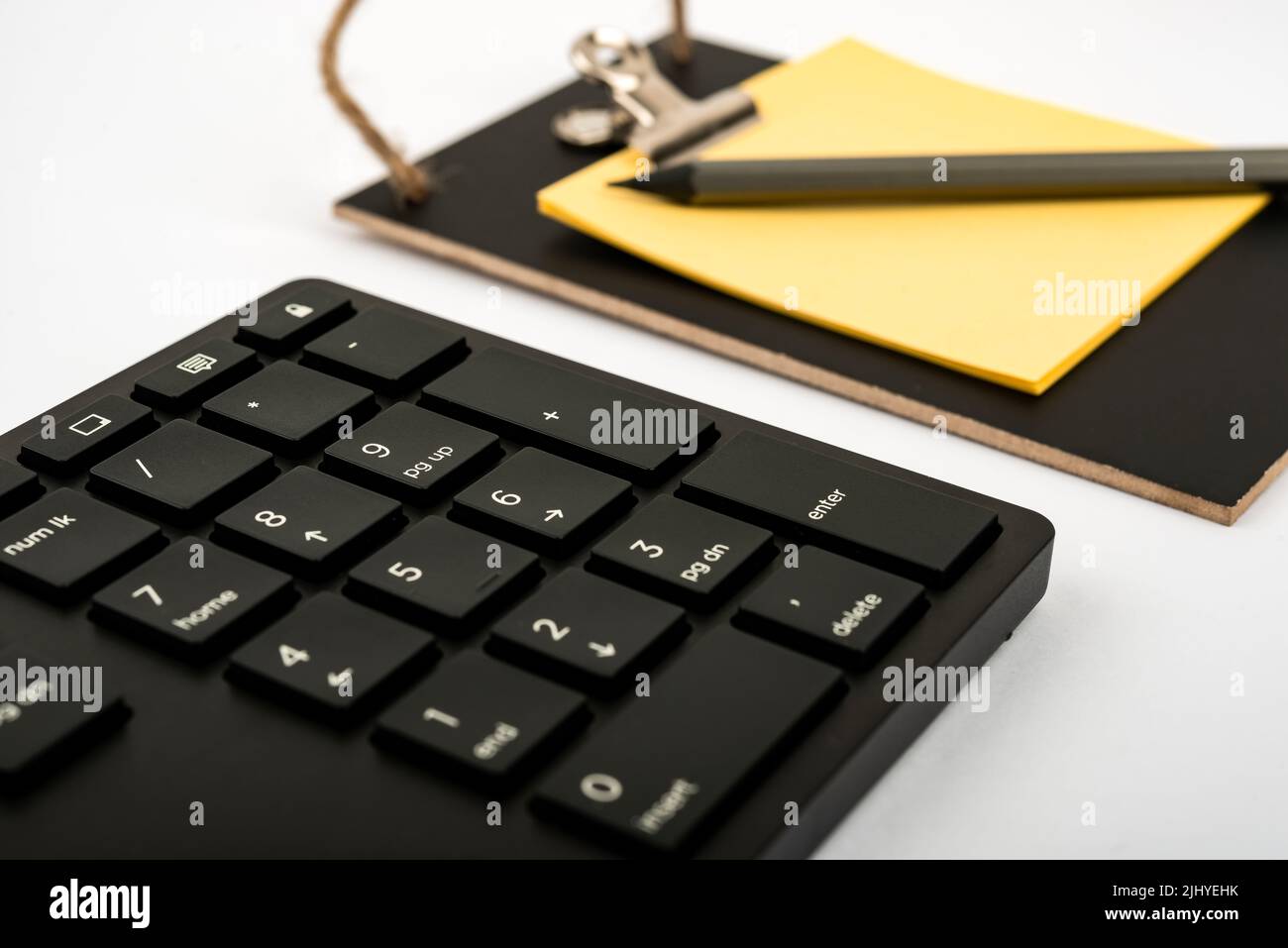 A part of a black computer keyboard, small paper pins and pencils ...