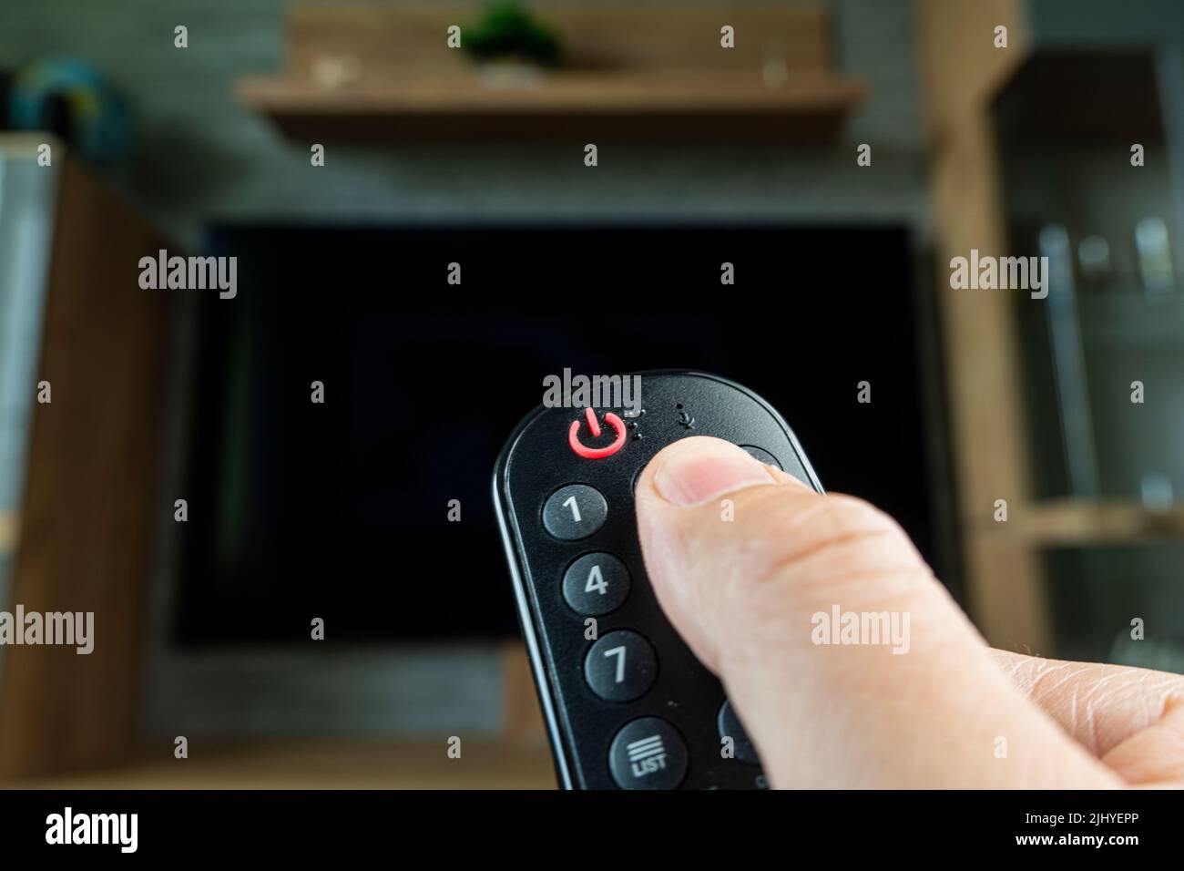 Television remote control changes channels thumb on the black TV screen ...