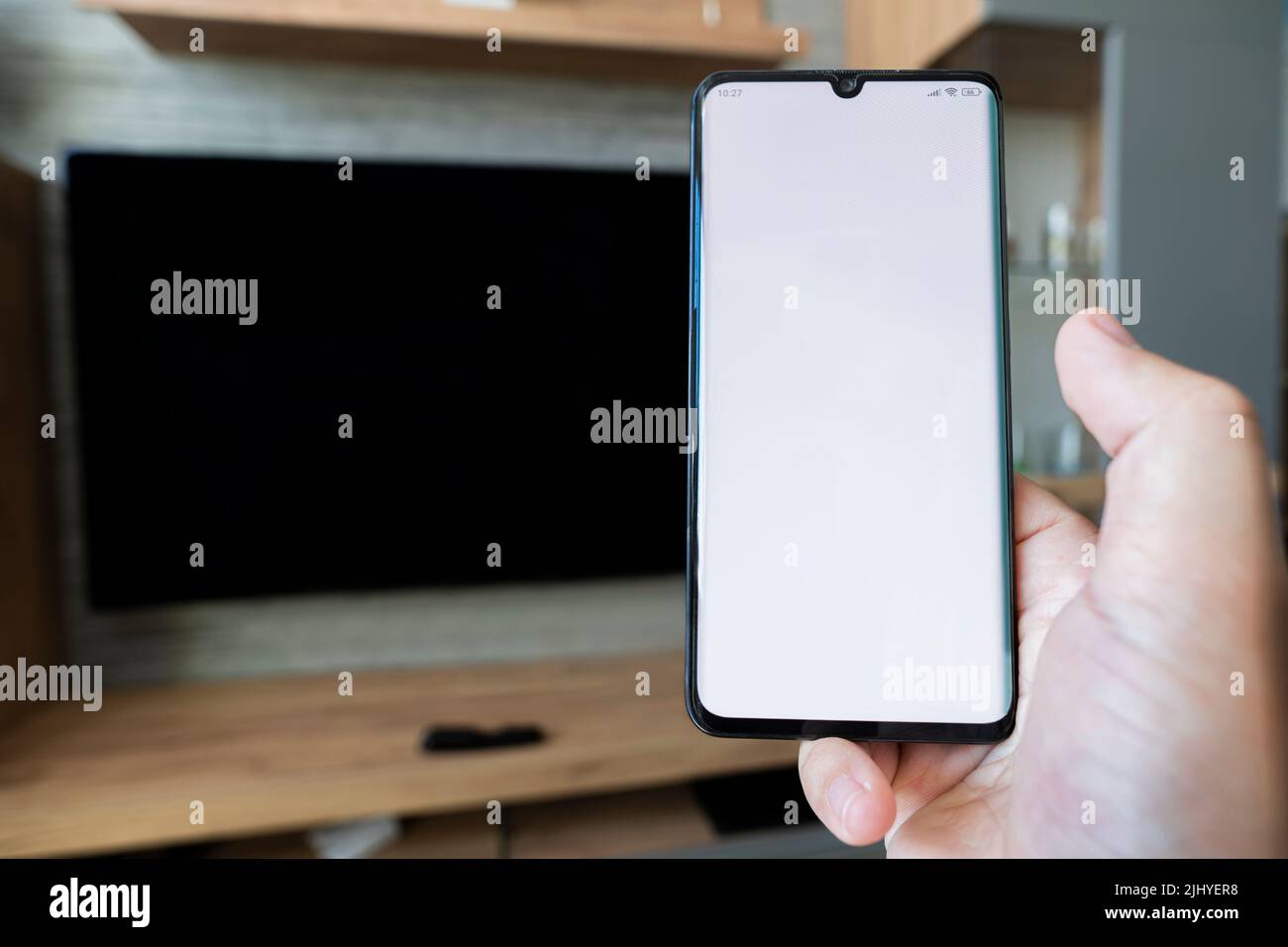 man hand tap on white screen smartphone with screen tv on background in ...