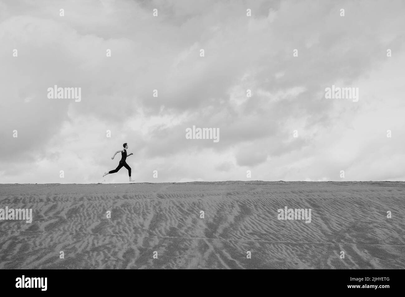 Lone man running on the sand through sandy desert Stock Photo - Alamy