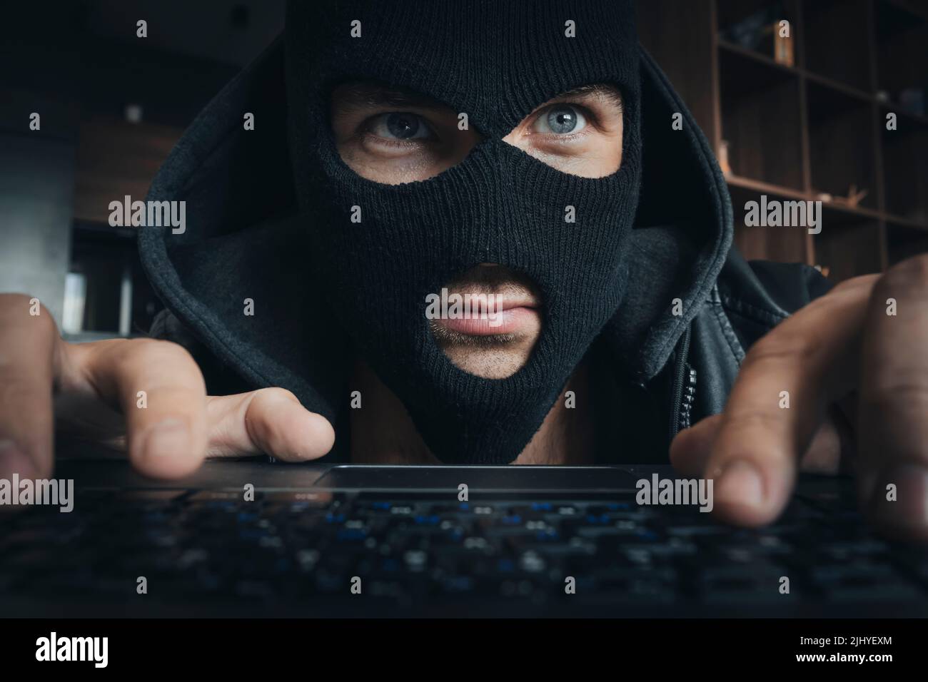 A man in a mask prints on the keyboard at a table in the dark Stock ...