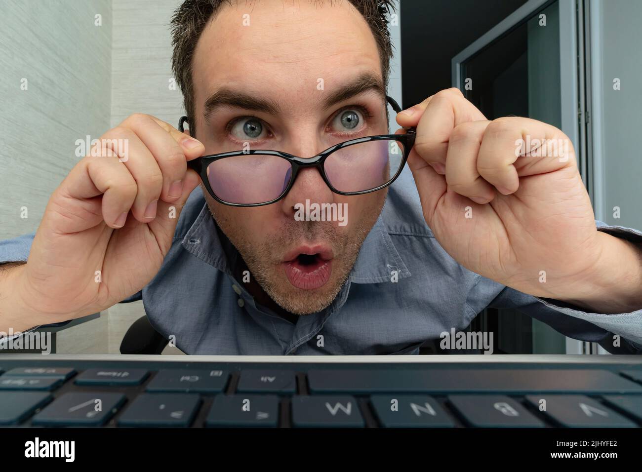 The young surprised man with his laptop computer. An employee in the ...