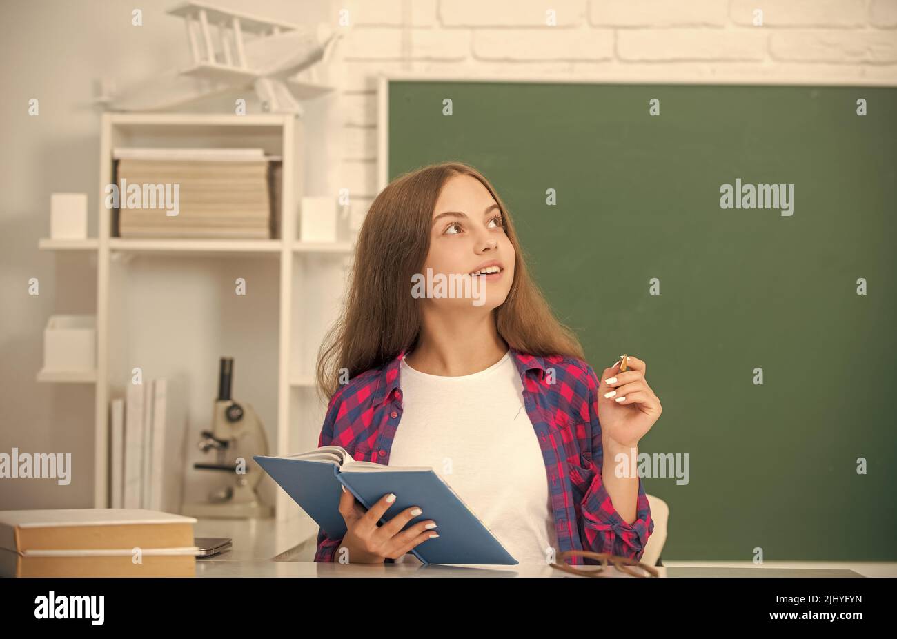 teen girl in high school making notes workbook at blackboard, wisdom ...