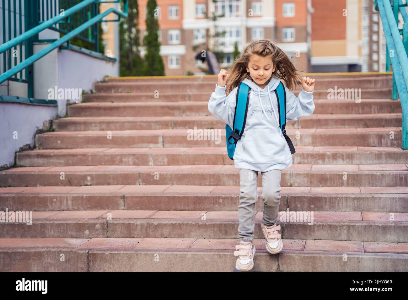 Back to elementary, primary school. Little sad girl with big backpack ...