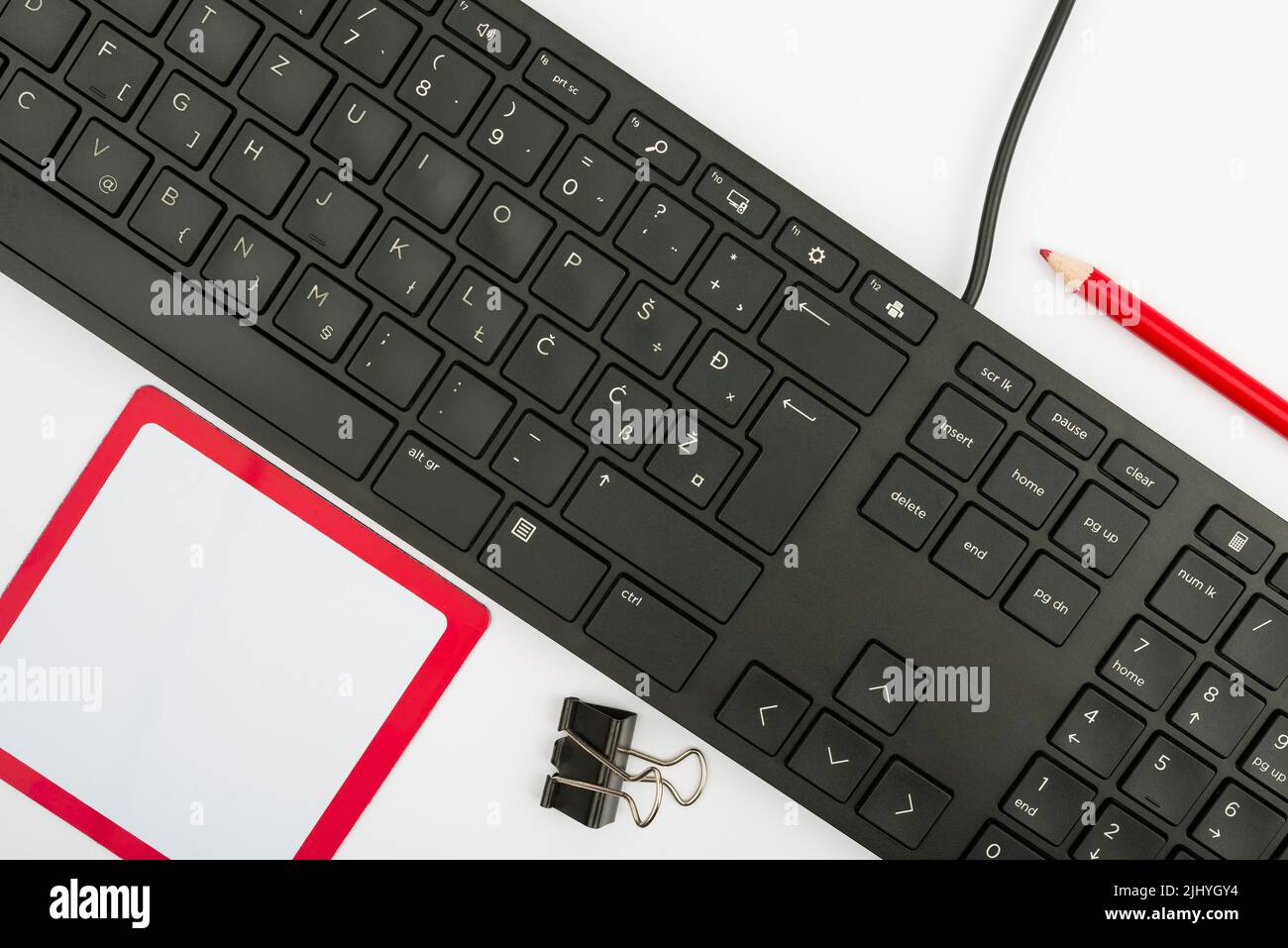 A top view of a computer keyboard with office stationery, diagonal ...