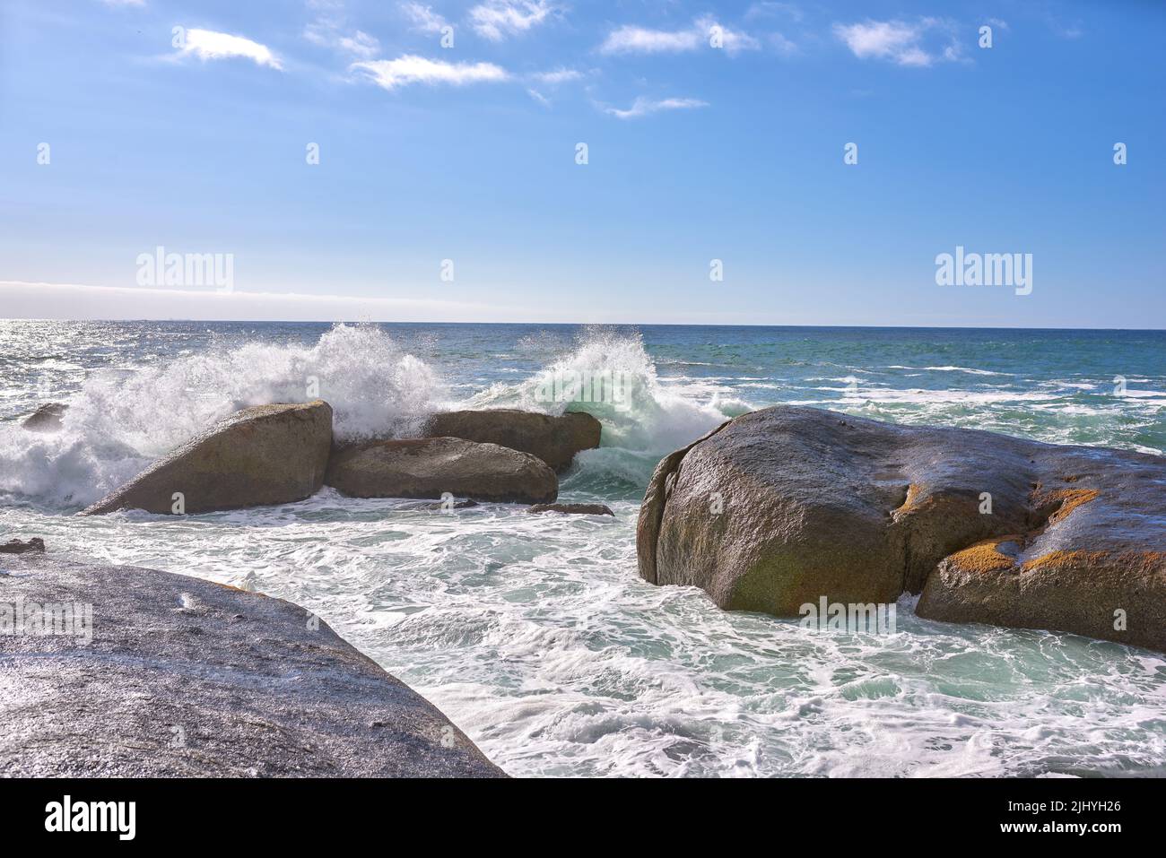 Scenic ocean view of beach with rocks or boulders and sea water washing ...