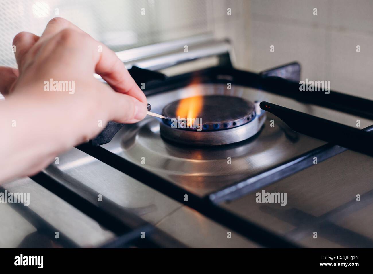 A woman's hand with matchstick lights gas stove in her apartment Stock ...